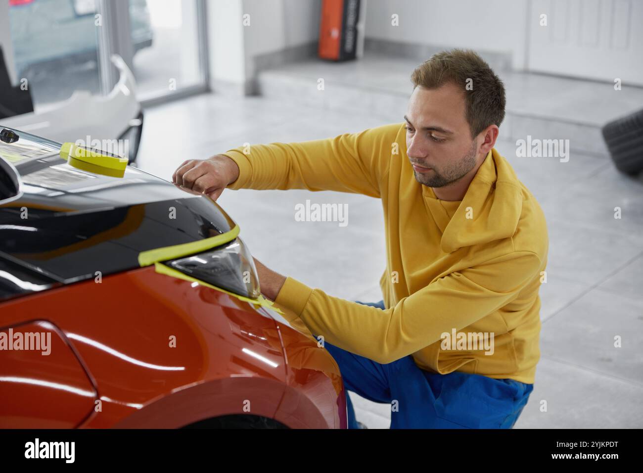 Man worker using masking tape to protect painted parts of body near ...