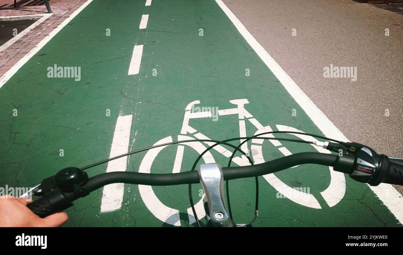 First person view of handlebars while cycling on a designated green ...
