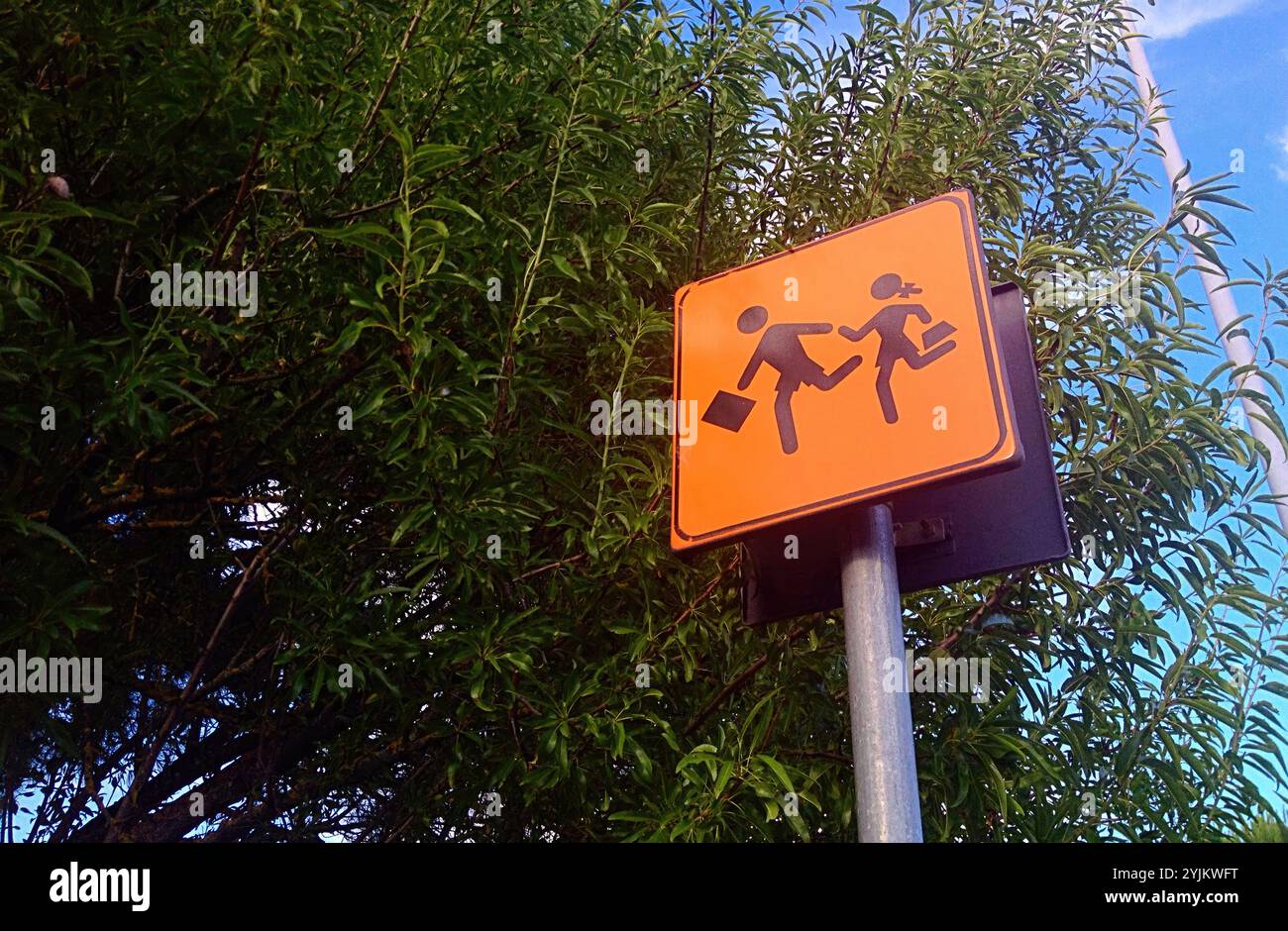 Orange school zone warning road sign with children running, placed near ...