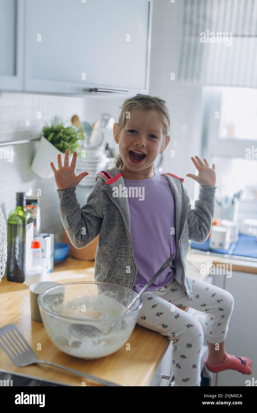 Cute little girl kid in the kitchen at home making pancakes. Children ...