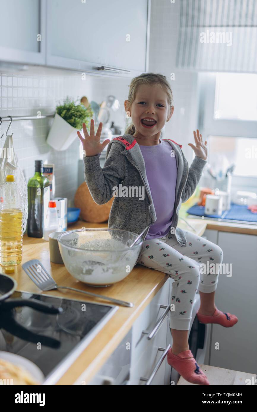Cute little girl kid in the kitchen at home making pancakes. Children ...