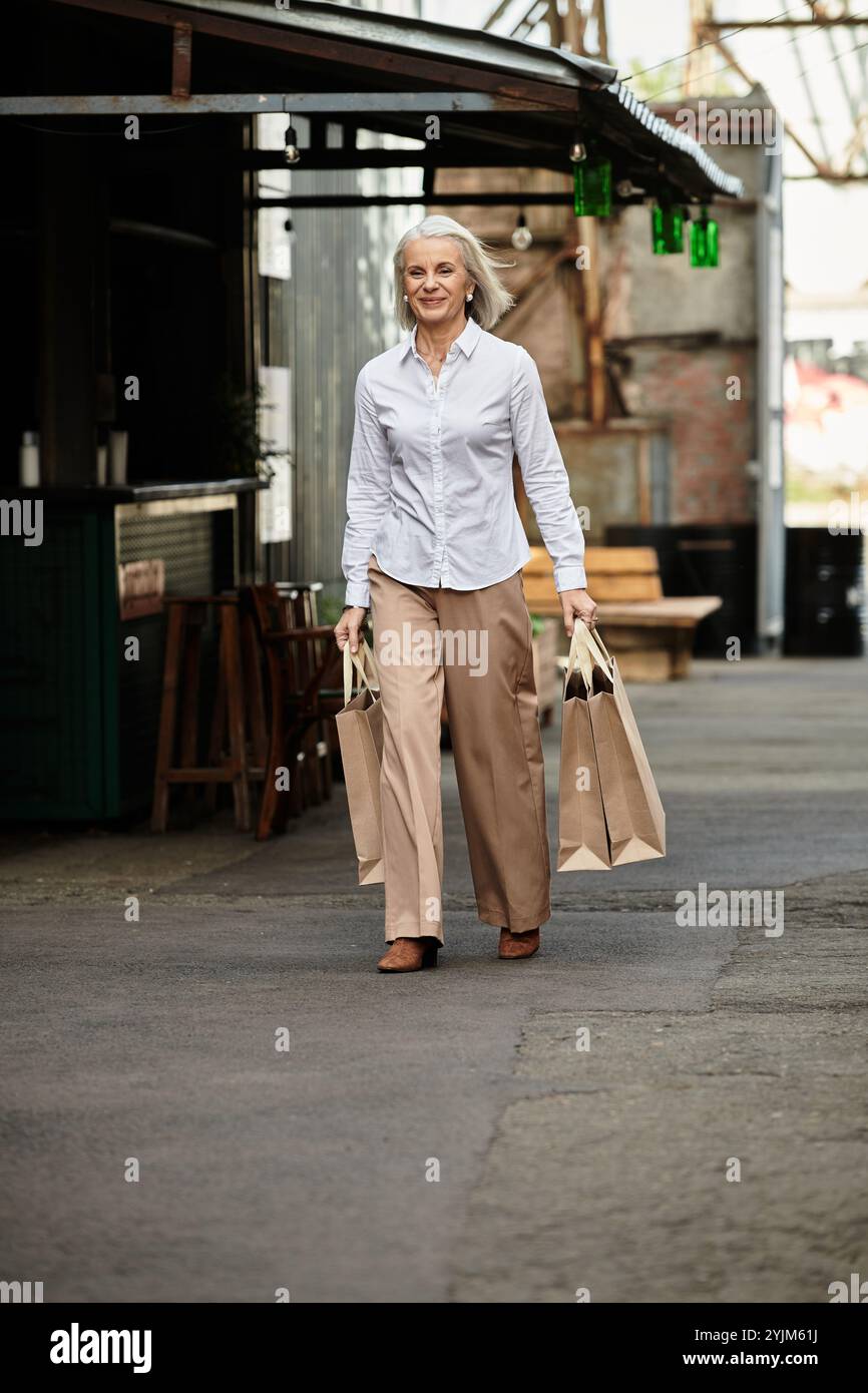 A beautiful mature woman enjoys her stroll, carrying shopping bags down ...