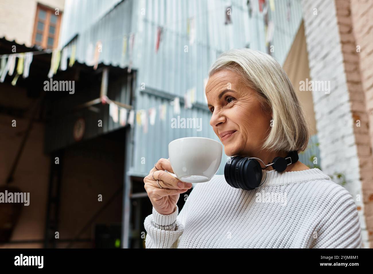 A mature woman with gray hair sips coffee and embraces a moment of ...