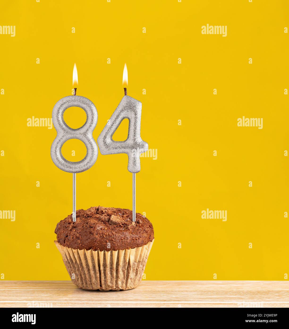 Chocolate cupcake with number 84 candle - Birthday on a yellow ...