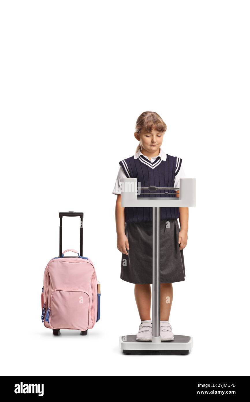 Schoolgirl with a backpack standing on a medical weight scale isolated ...