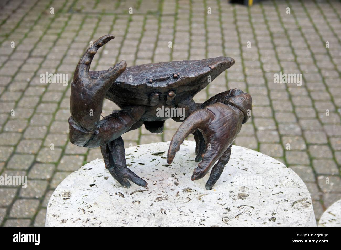 A sculpture of a crab waving it's claw in a humourous way on a stone ...