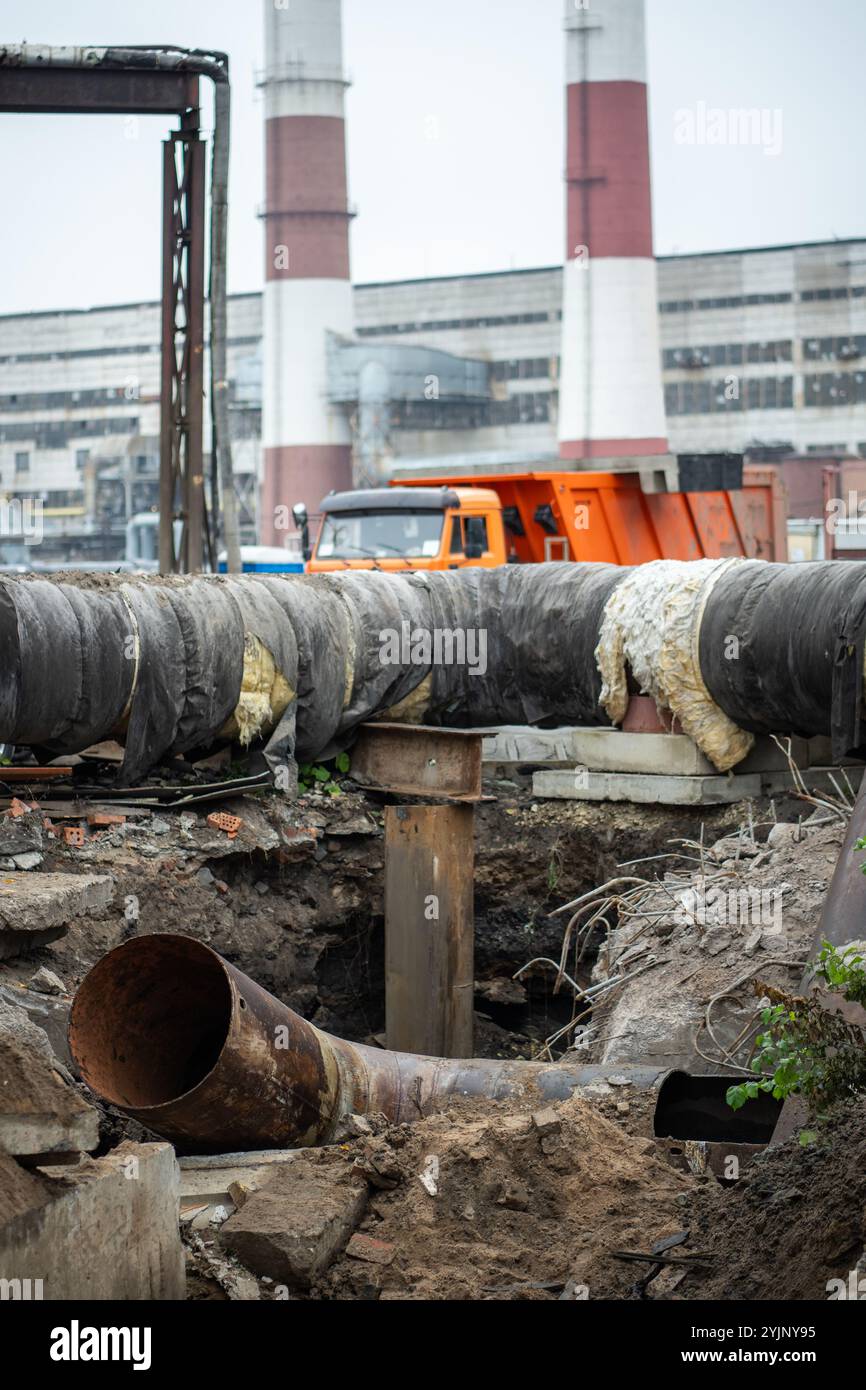 Scattered fragments of water, gas pipes in excavated trench. Worn pipe ...