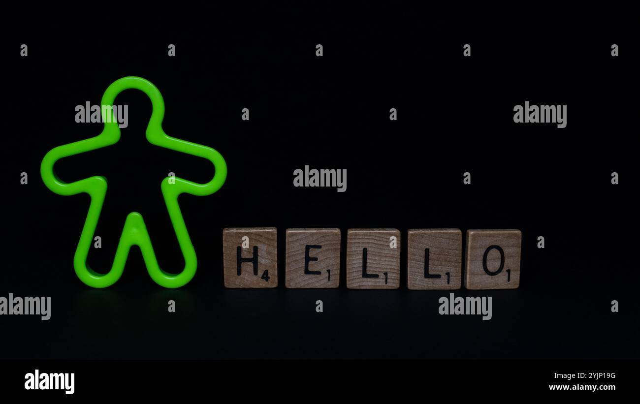 Fluorescent green plastic man standing next to the scrabble wooden ...