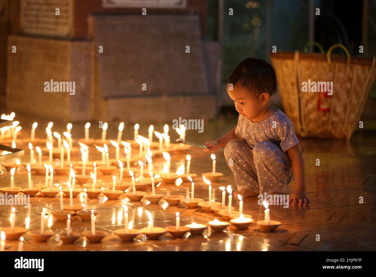 Yangon, Myanmar. 15th Nov, 2024. A child lights a candle to celebrate ...