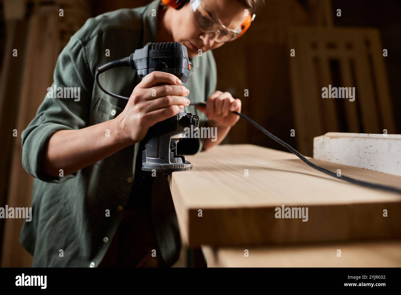 A dedicated carpenter is focused on shaping wood using a power tool in ...