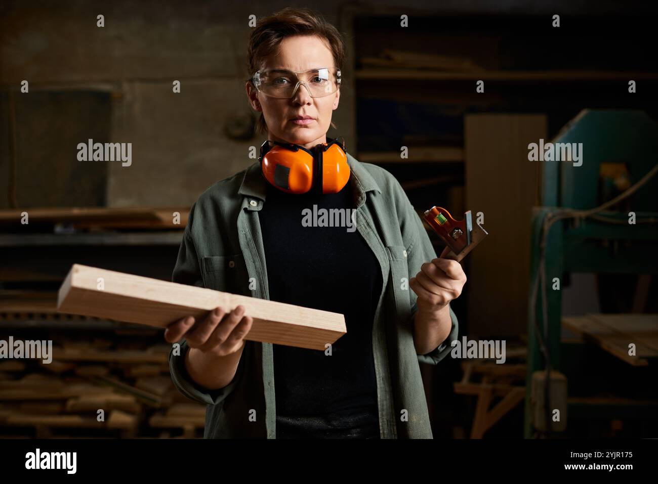 A female carpenter works diligently with wood, measuring and preparing ...