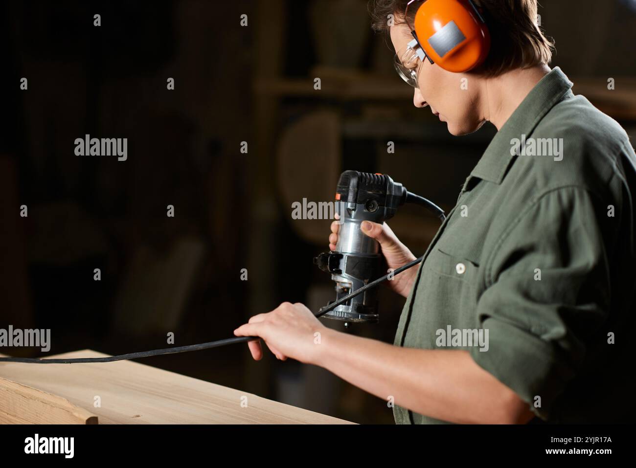 A focused carpenter operates a router while shaping wood in a well ...