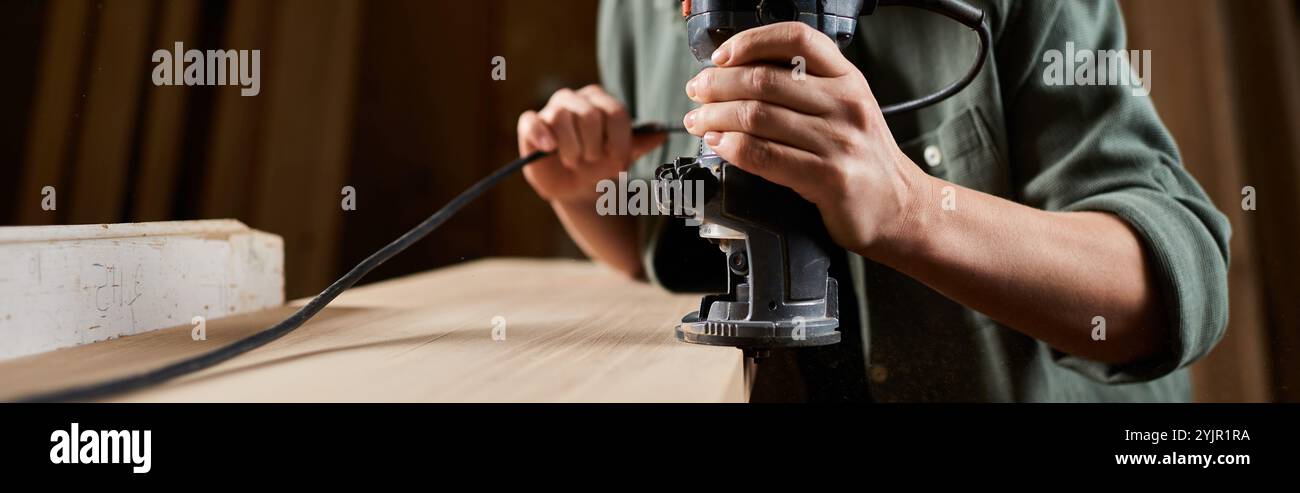 A focused female carpenter uses a router on wood, shaping materials in ...