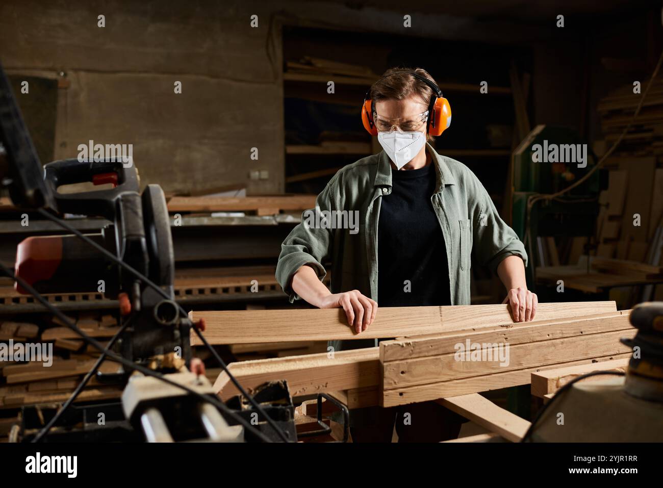 A focused carpenter works diligently with wooden planks in a well ...
