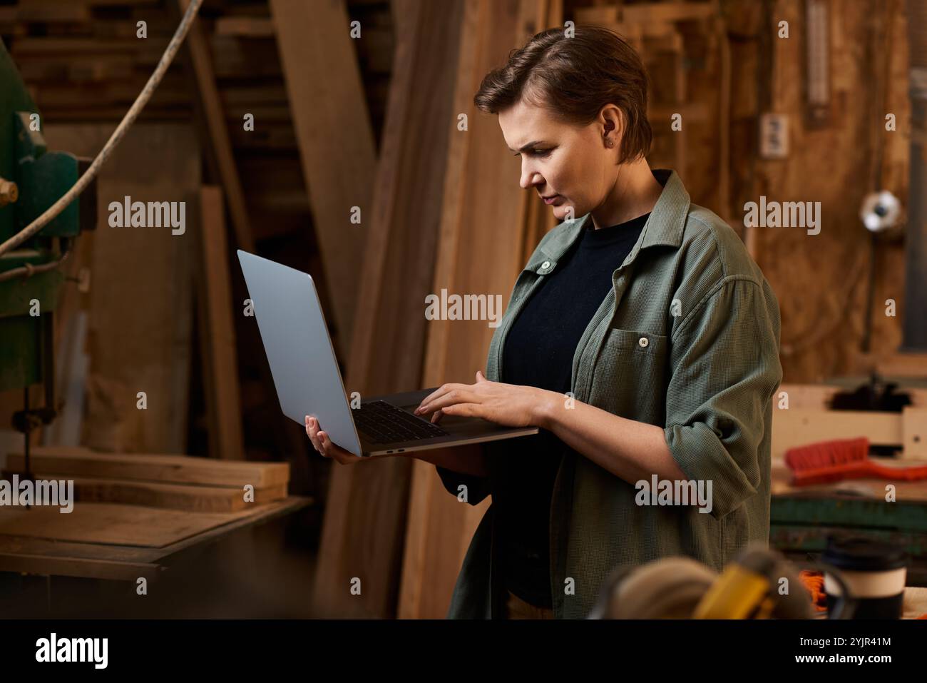 In a well-equipped workshop, a talented female carpenter focuses on her ...