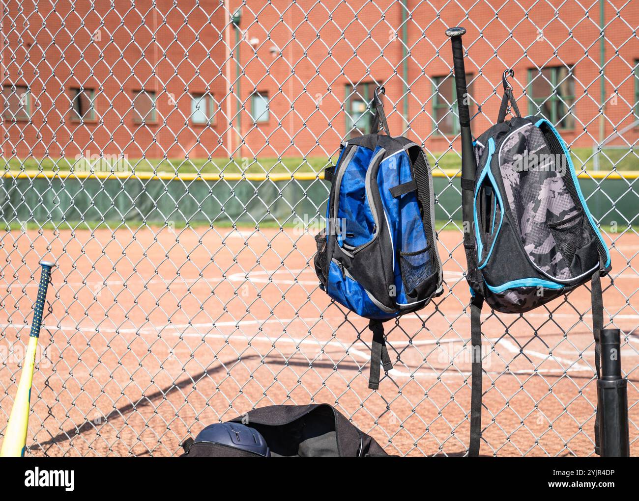 Baseball backpacks hanging on fence youth sports Stock Photo - Alamy