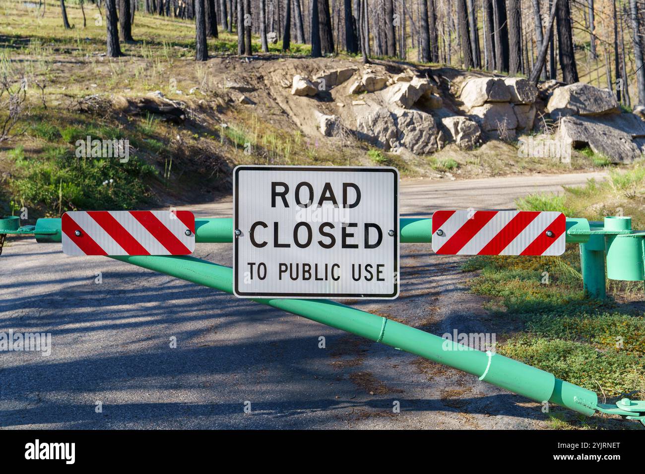 A road closed to public use sign in front of a gate, preventing access ...