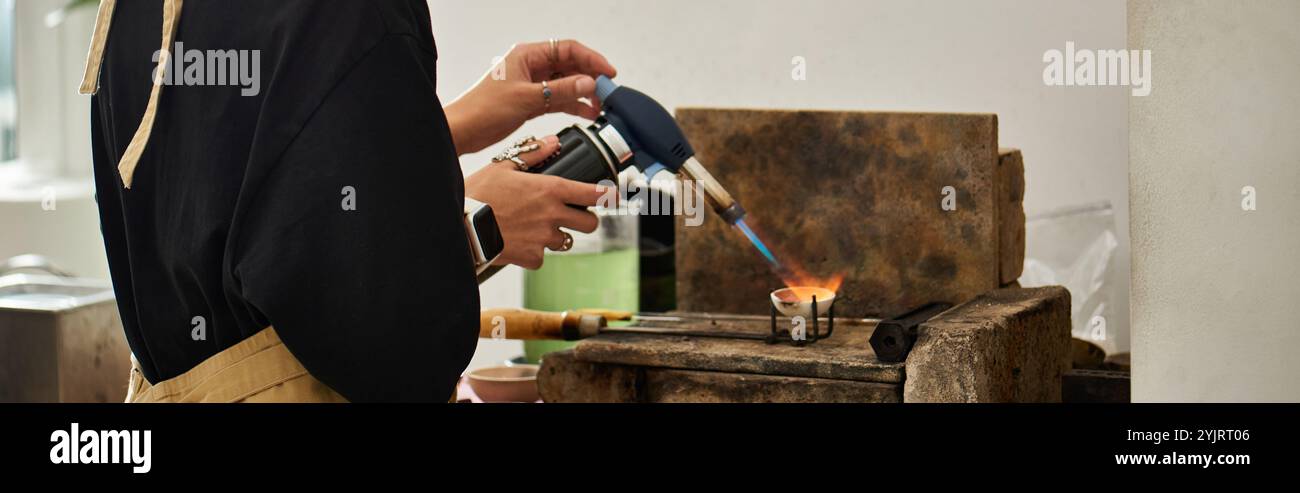A woman using torch in a warm studio filled with creating tools Stock ...