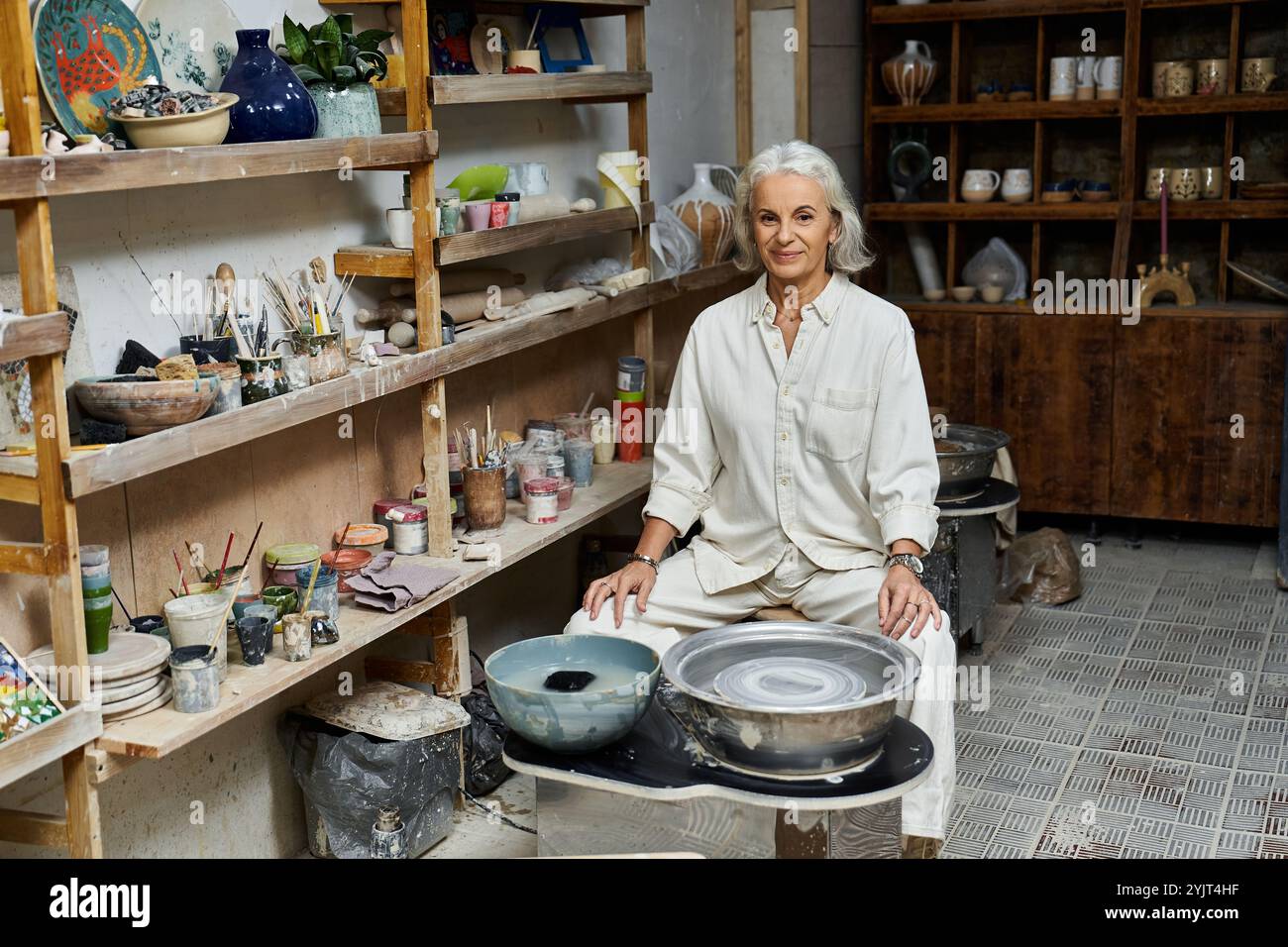 A mature woman creates unique pottery pieces in her artistic, tool ...