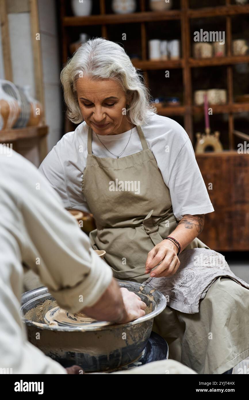 A mature woman crafts pottery at a tranquil studio, engaging deeply in ...