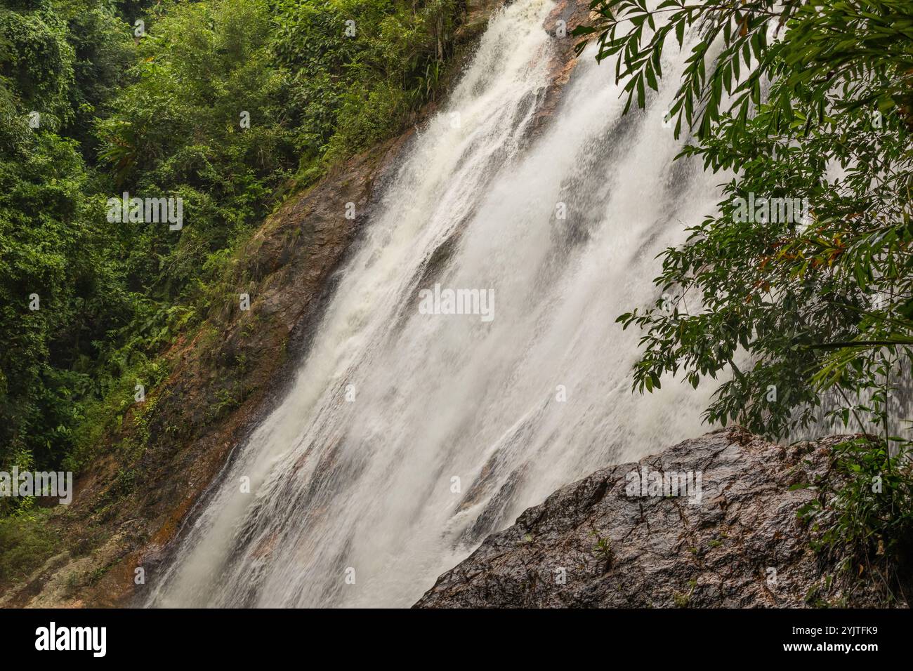 A powerful waterfall cascading down a steep, rocky cliff surrounded by ...