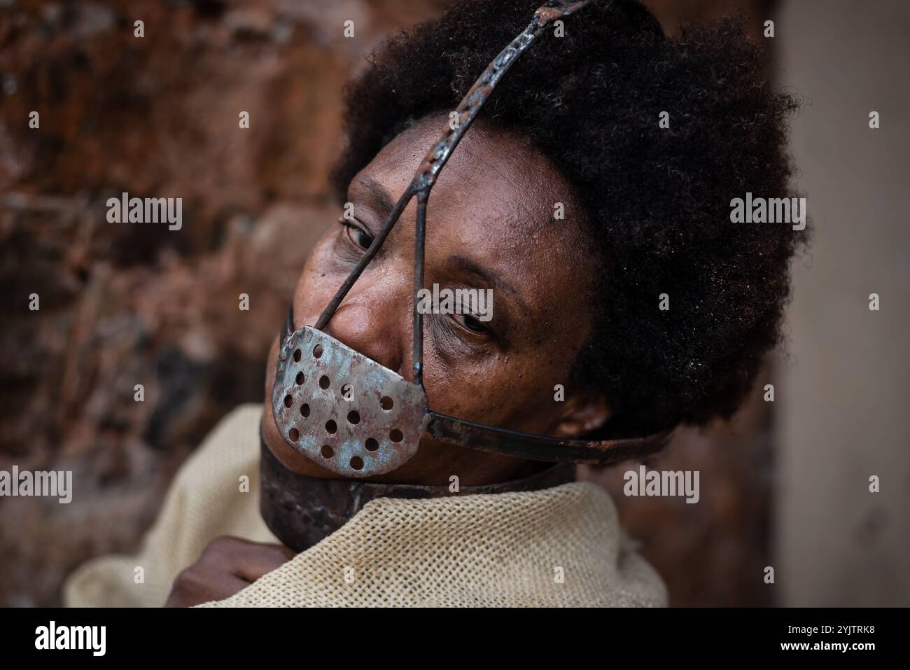Portrait of a black woman's face with an iron mask stuck in her mouth ...