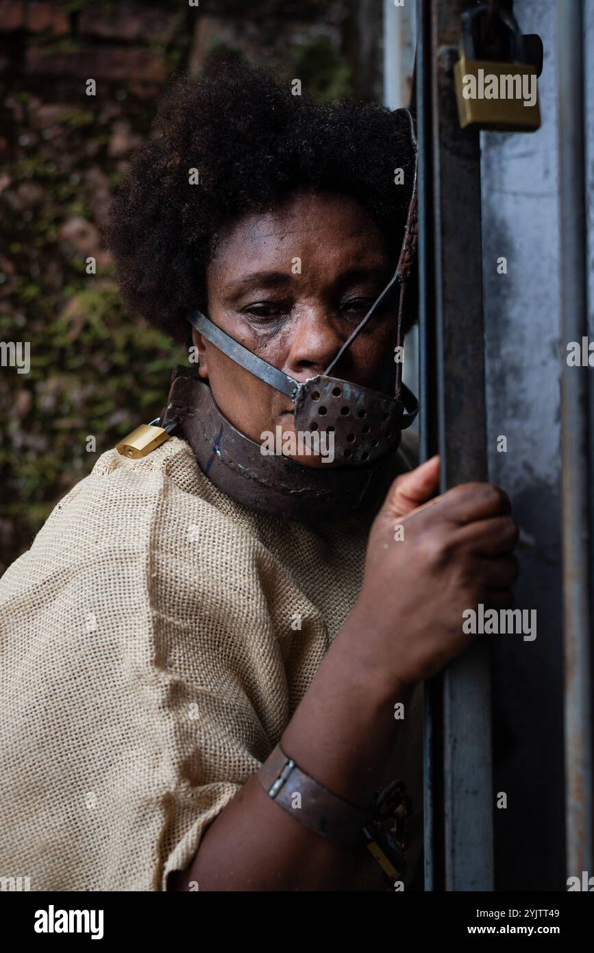 Black woman dressed as a slave, chained with an iron mask on her mouth ...