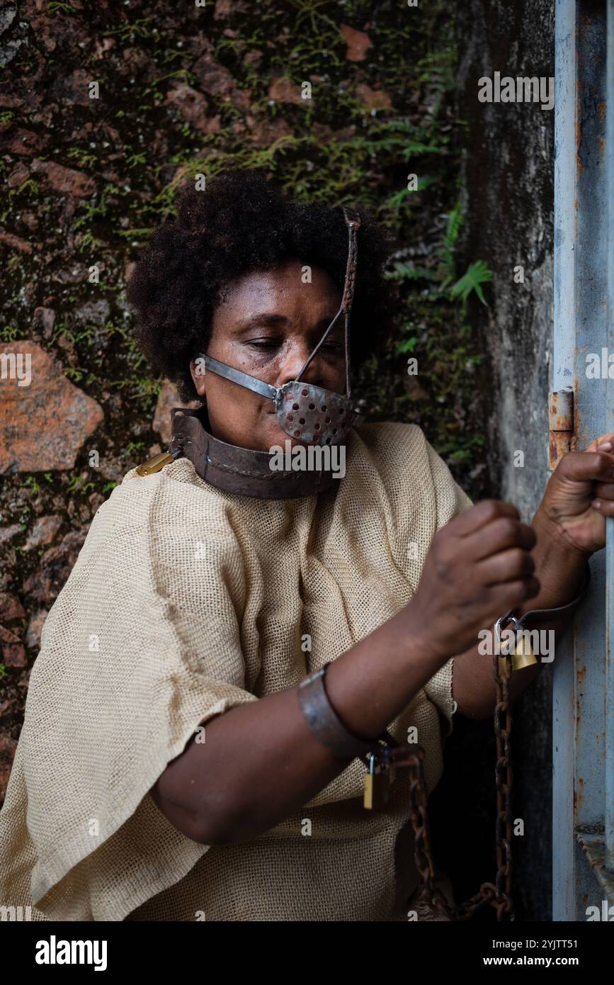 Black woman dressed as a slave, chained with an iron mask on her mouth ...