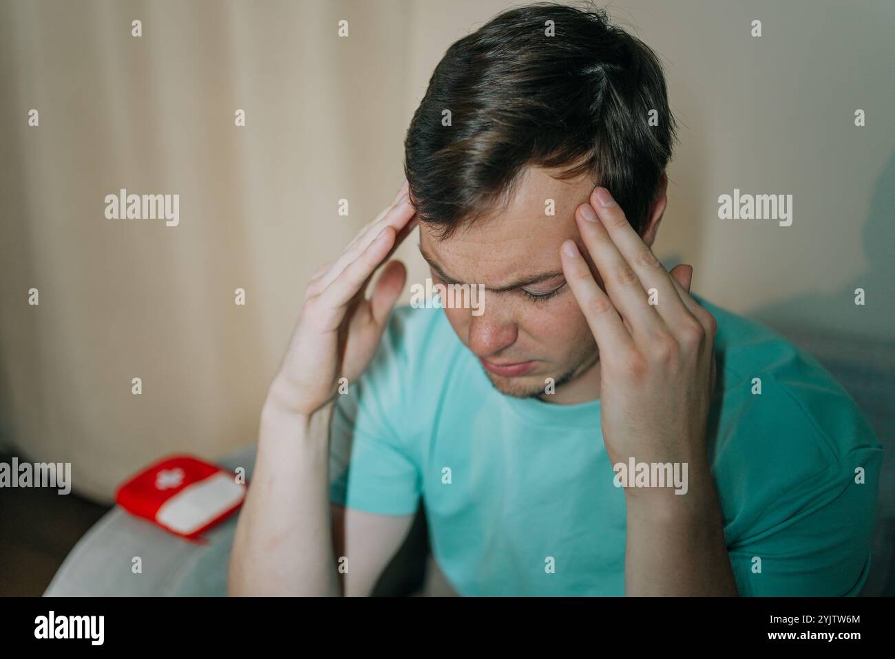 Young man in casual clothes touching his temples, suffering from a ...
