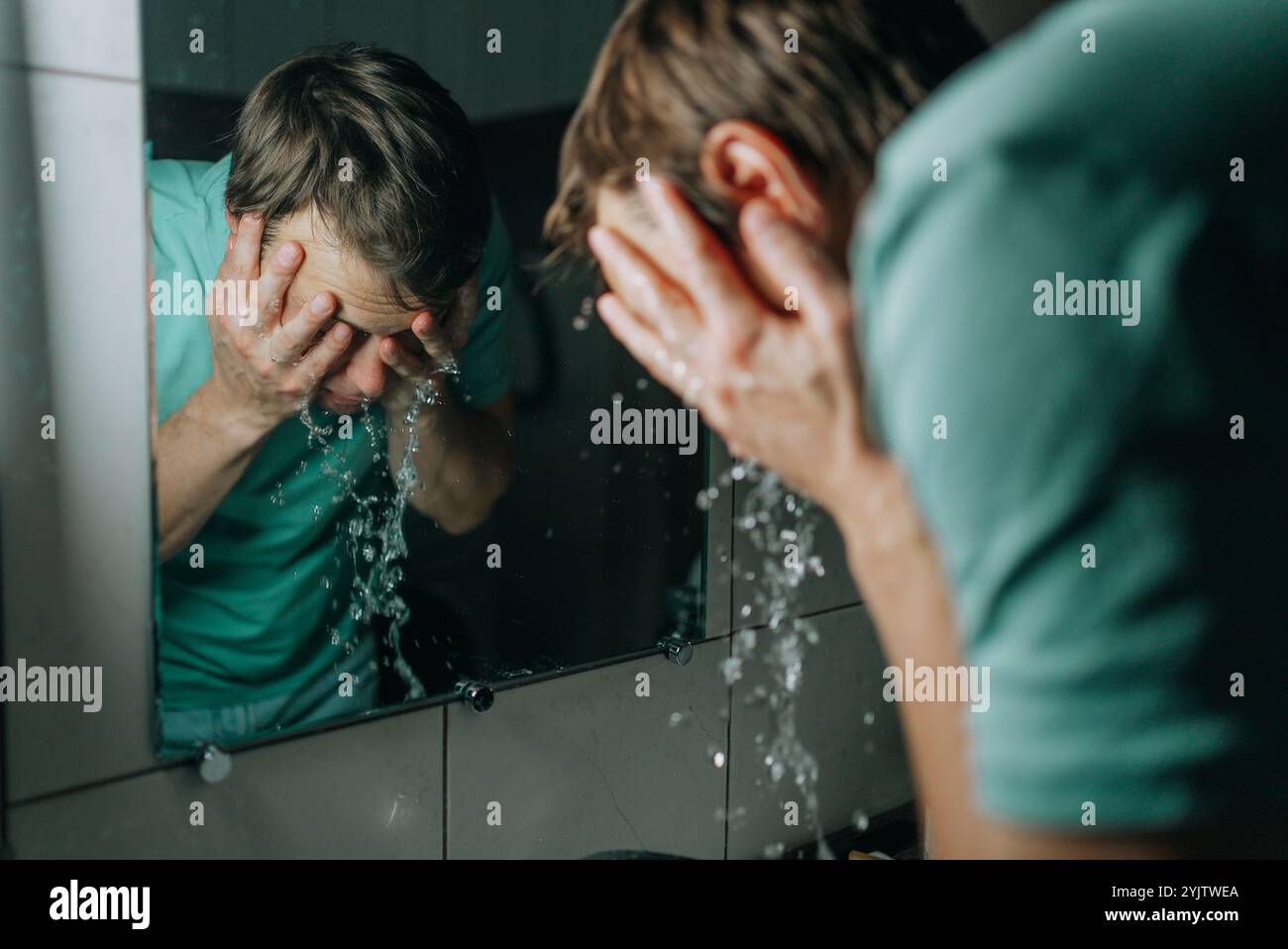 Man splashing water on his face while washing in the bathroom sink ...
