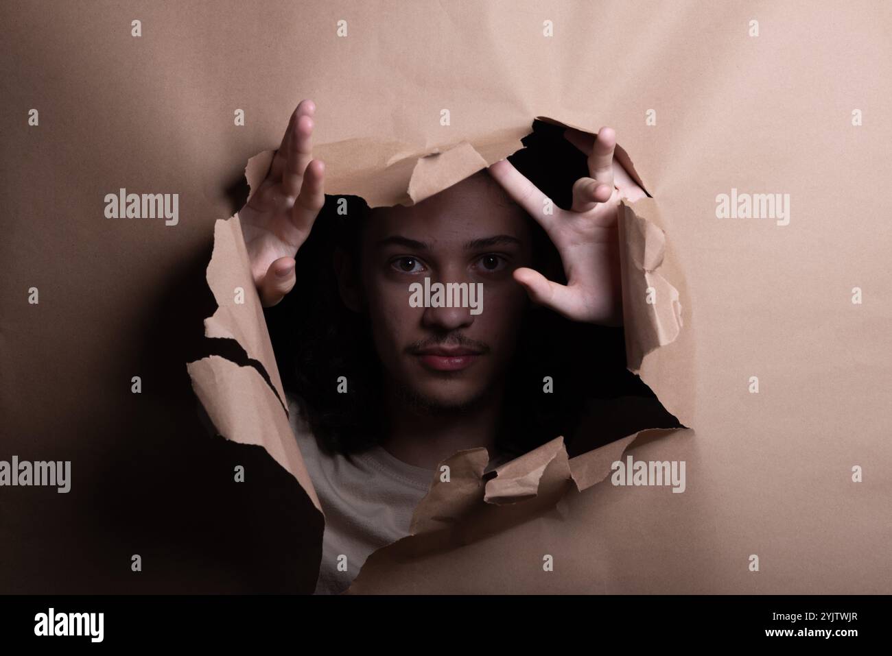 Man face and head sticking out and looking through a hole in brown ...