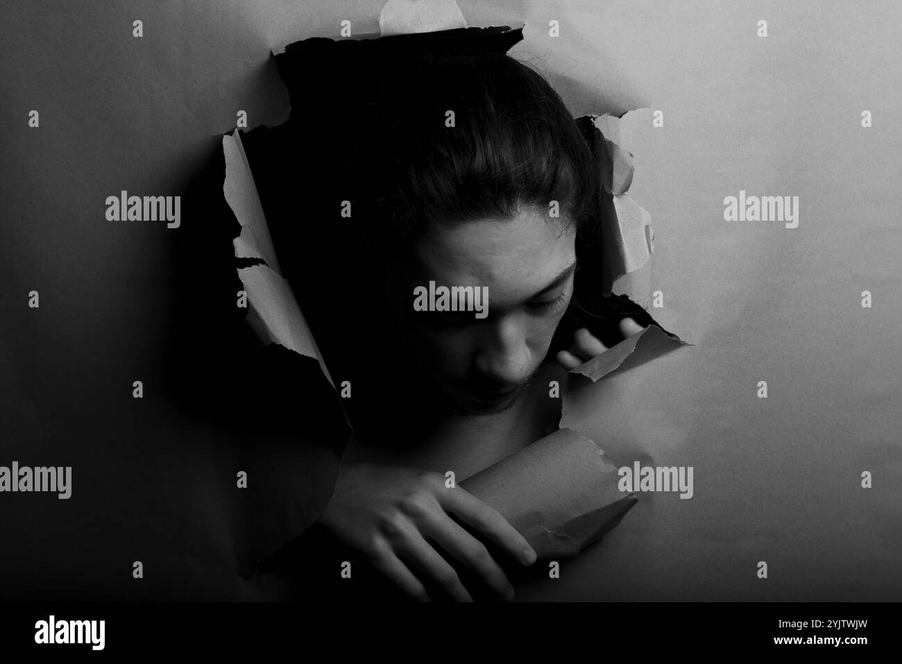 Man head sticking out and looking through a paper hole with his hands ...