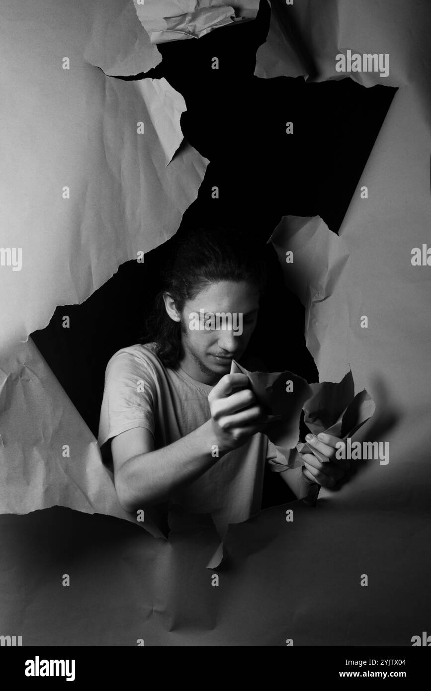 A man peering through a hole in a sheet of brown paper. Tearing the ...