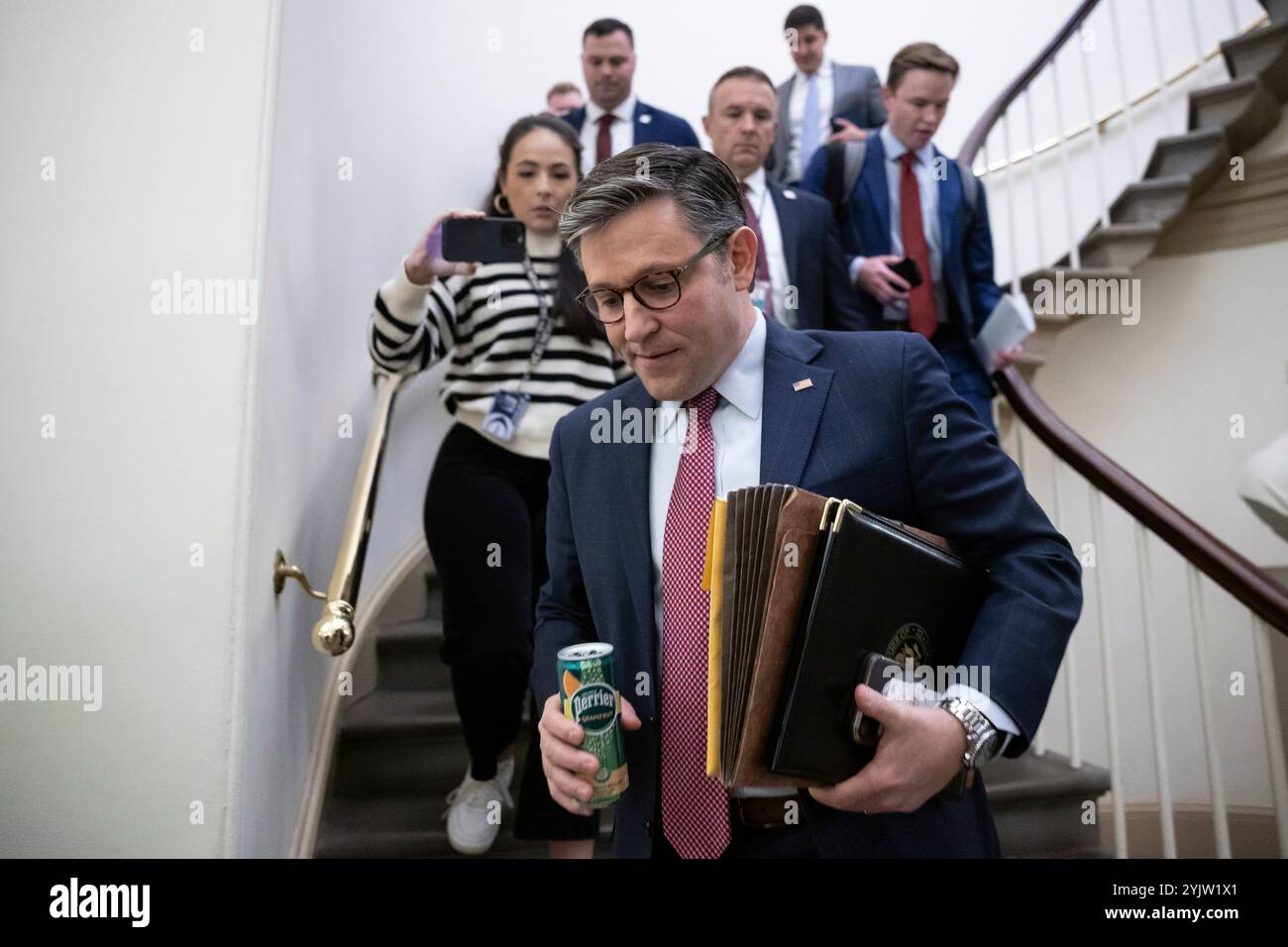 House Speaker Mike Johnson (R-La.) is followed by a reporter, aides ...