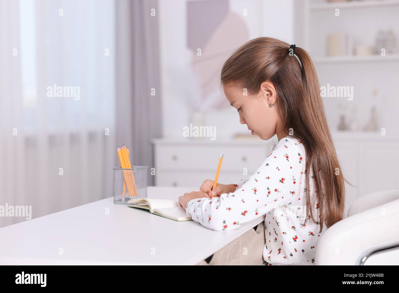 Girl with correct posture doing homework at white desk indoors Stock ...