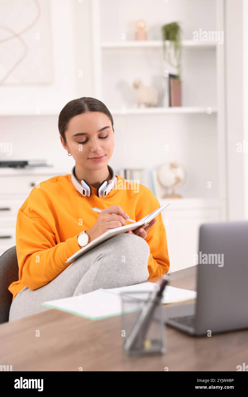 Student with headphones taking notes while studying indoors Stock Photo ...