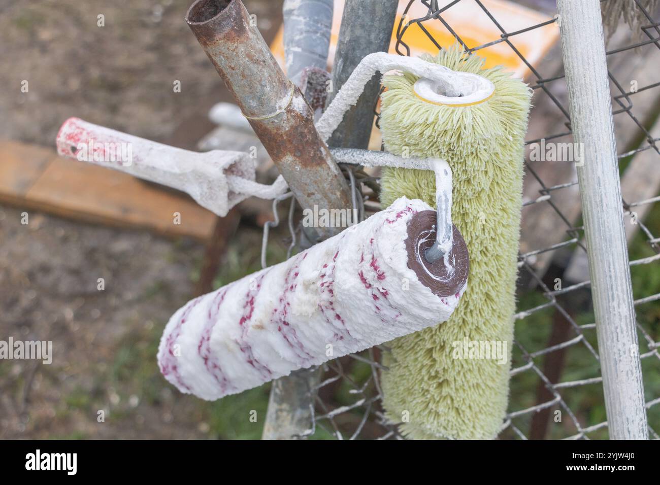 A paint roller and brush hang on the fence, ready for painting in an ...
