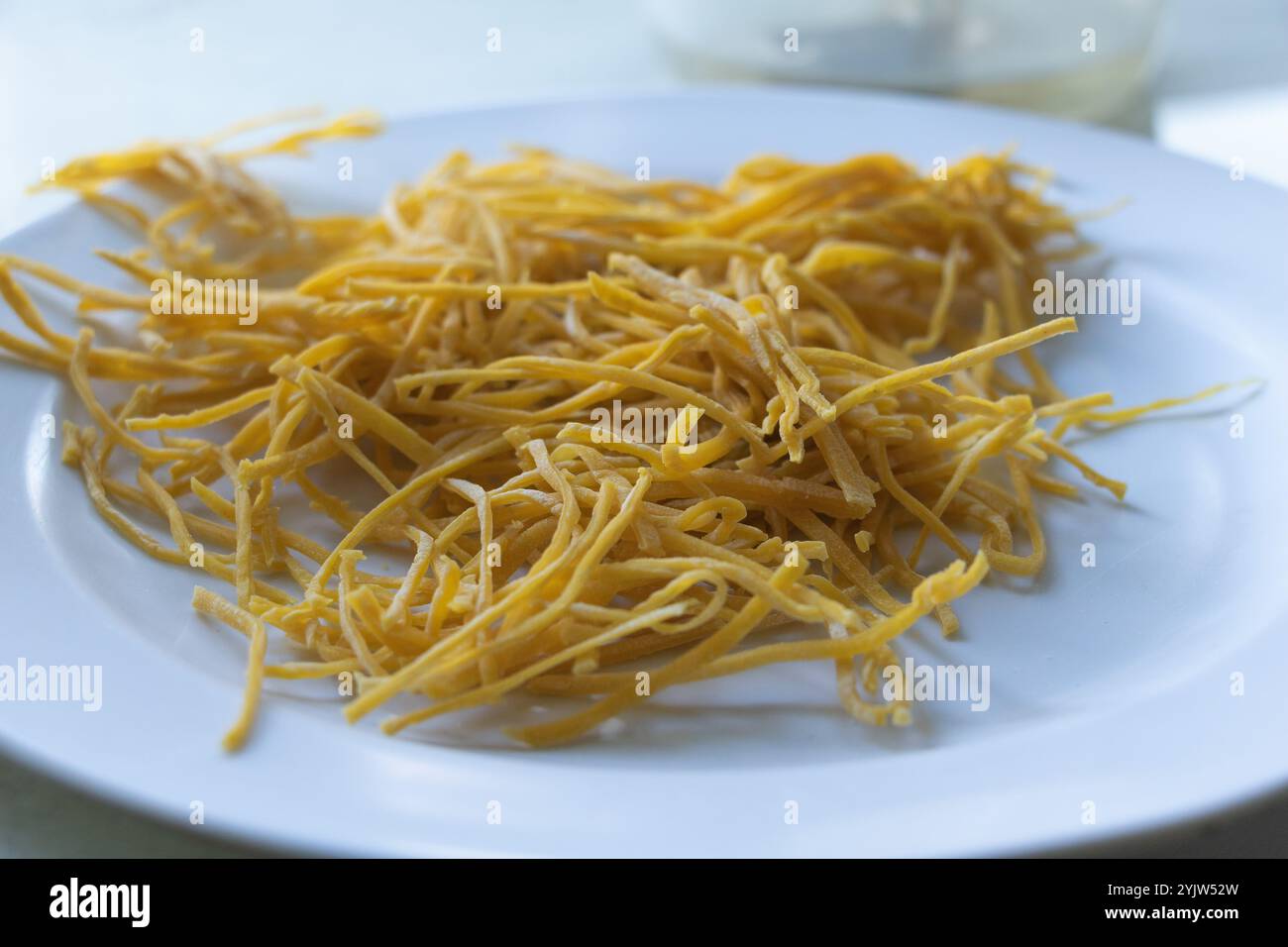 A plate of yellow noodles made from broad and narrow strips, resembling ...