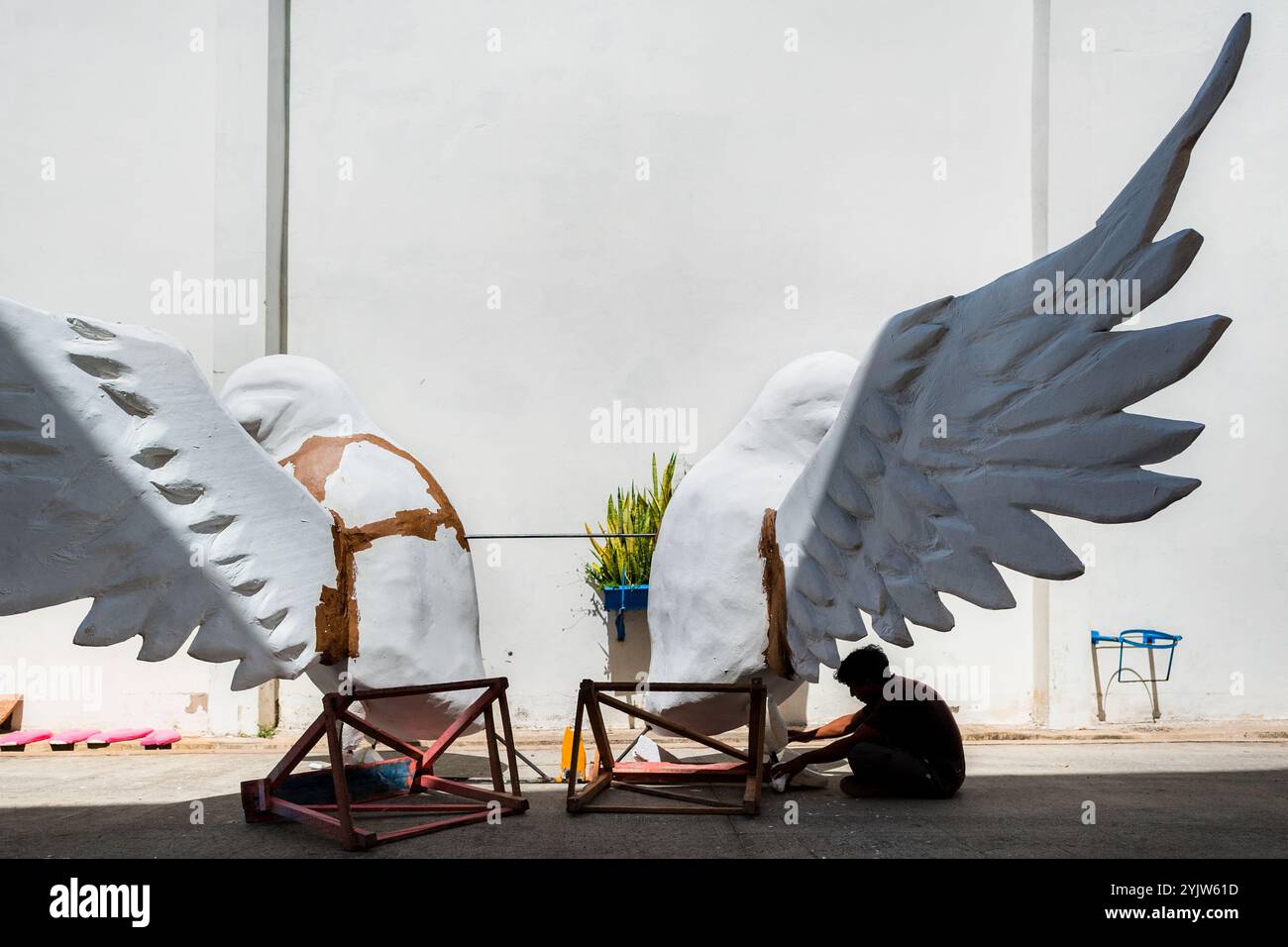 A Colombian artisan works on paper-mâché sculptures of parrots for an ...