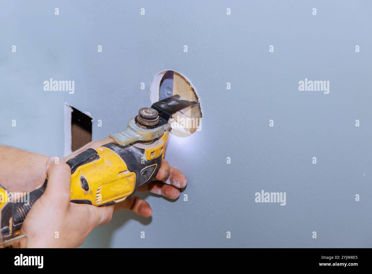 Contractor carefully operates power tool to create opening in a blue ...