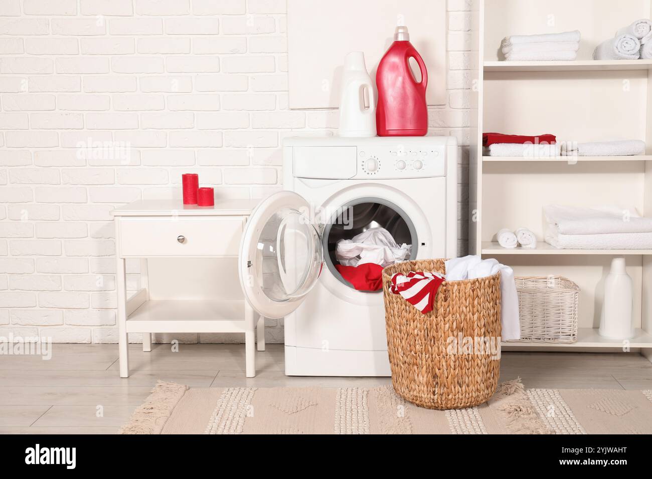 Washing machine, detergents and basket with laundry in room Stock Photo ...