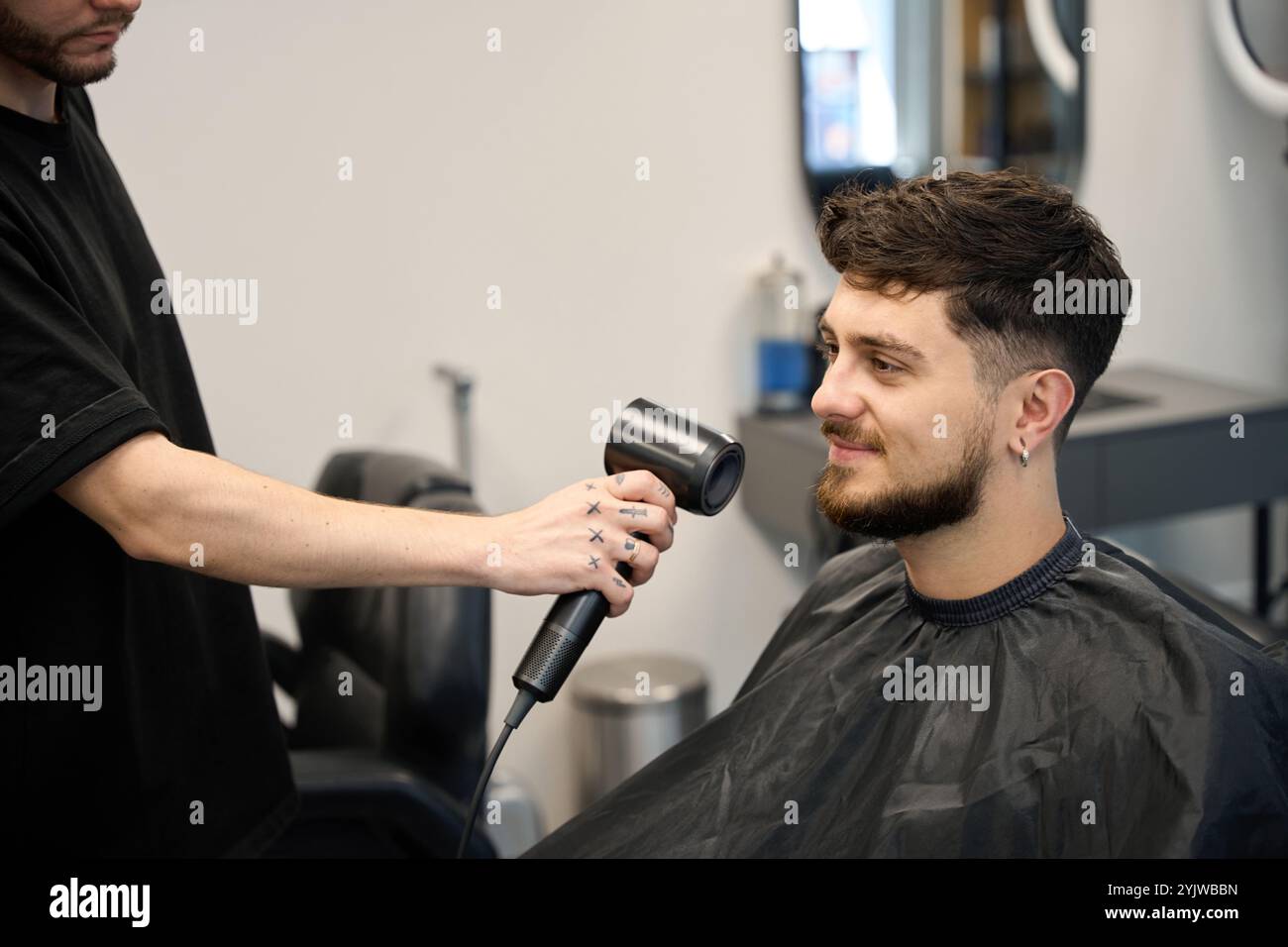 Professional uses dryer to style and shape client hair Stock Photo - Alamy
