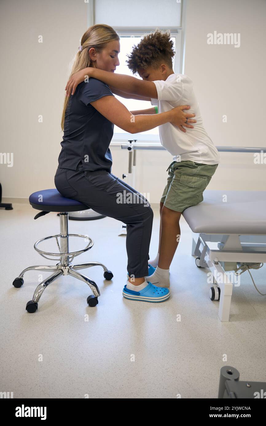 Teenage boy practices balance exercises with the therapists guidance ...
