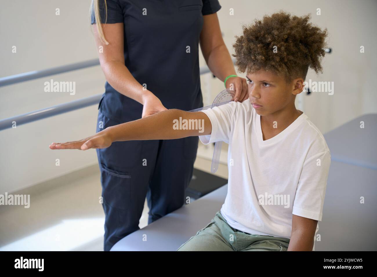 Doctor supervises a young patients arm movement exercise Stock Photo ...