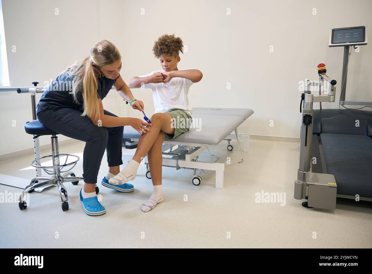 Physical therapist tests the muscle reflexes of a teenage boy Stock ...