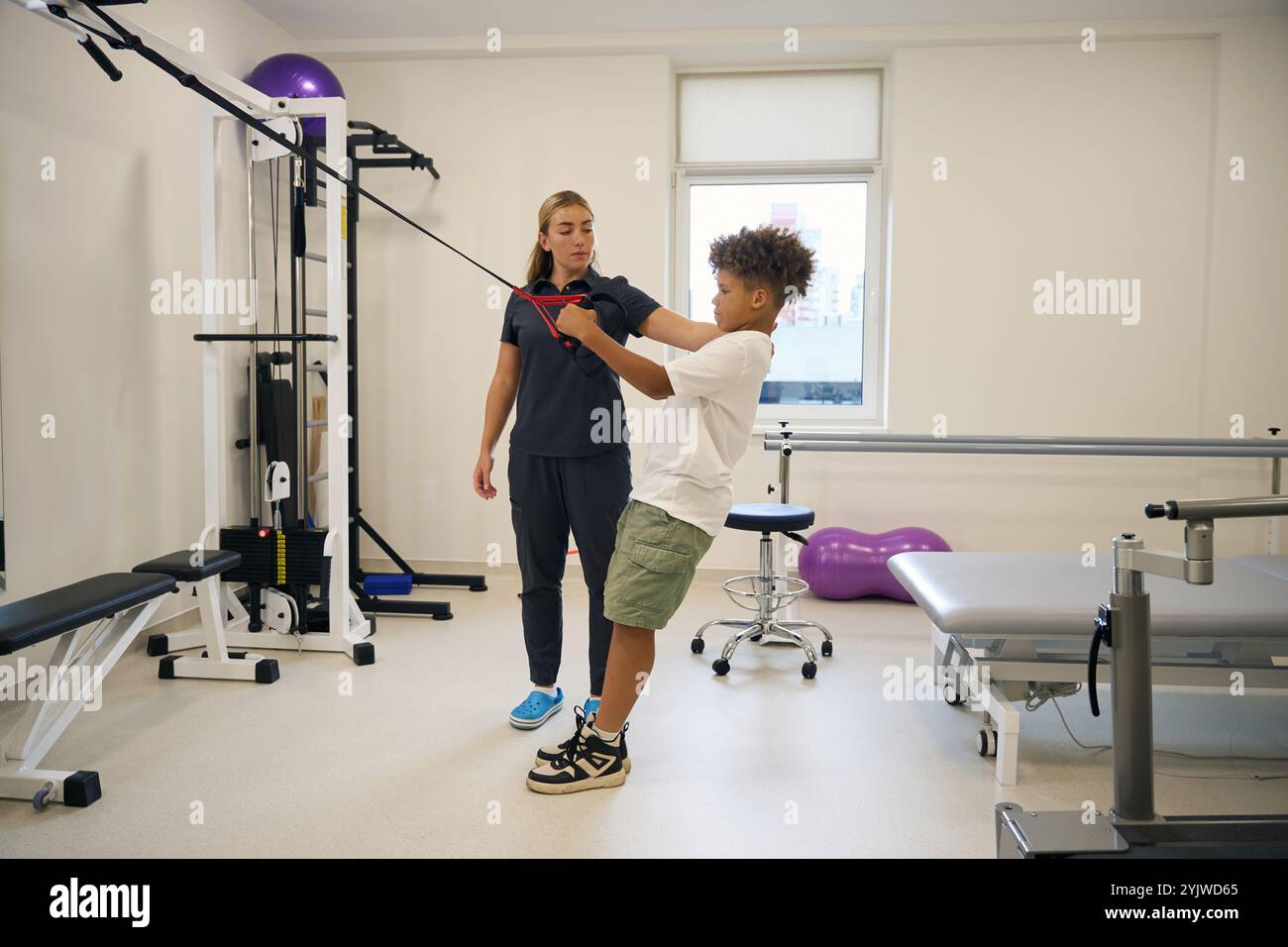 Young patient exercises using resistance band to improve posture and ...