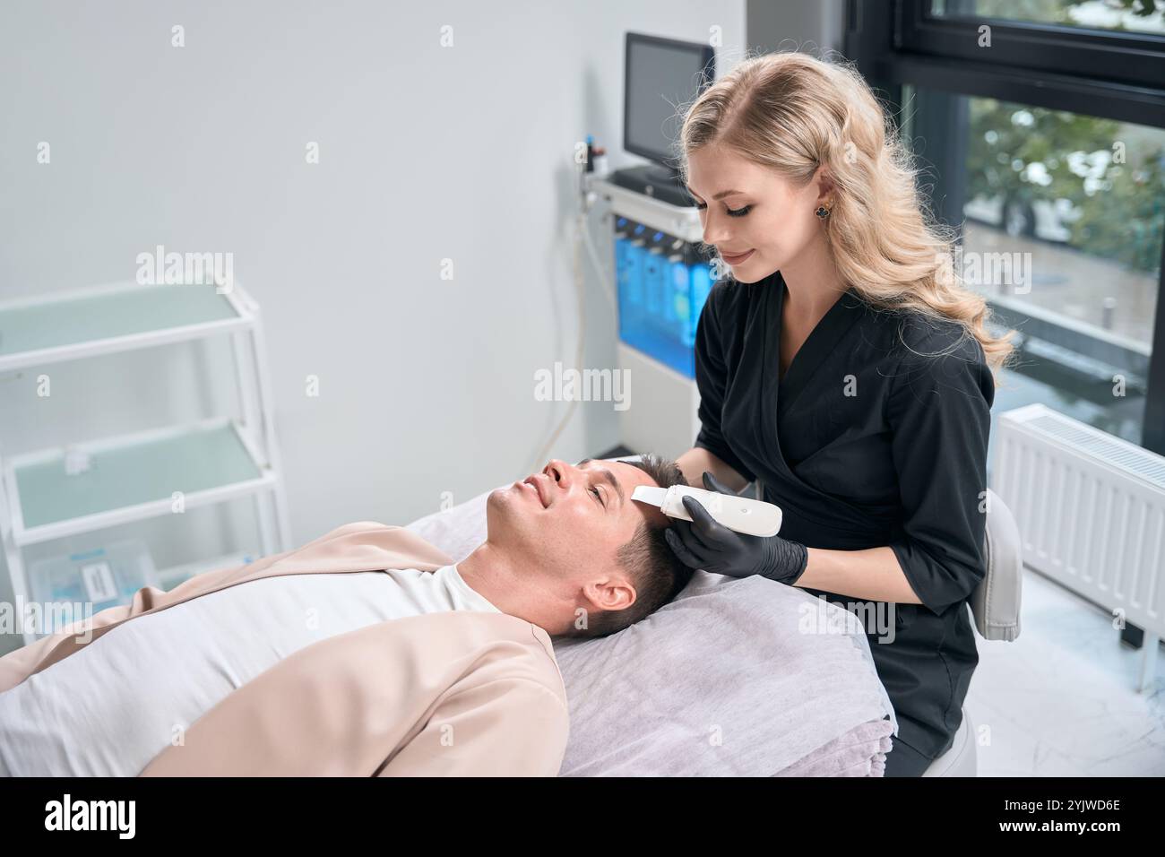Woman cosmetologist using ultrasonic scrubber to remove impurities from ...