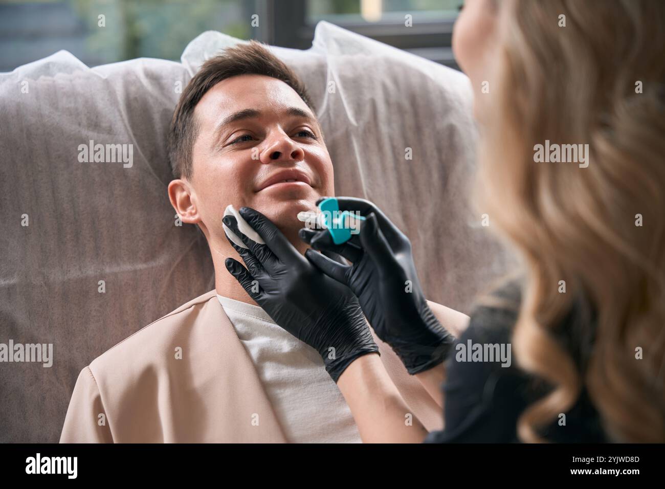 Woman cosmetologist correcting shape of male client cleft chin Stock ...