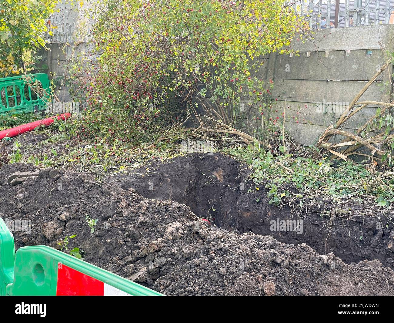 road excavation surrounded by green safety barriers and tools ...
