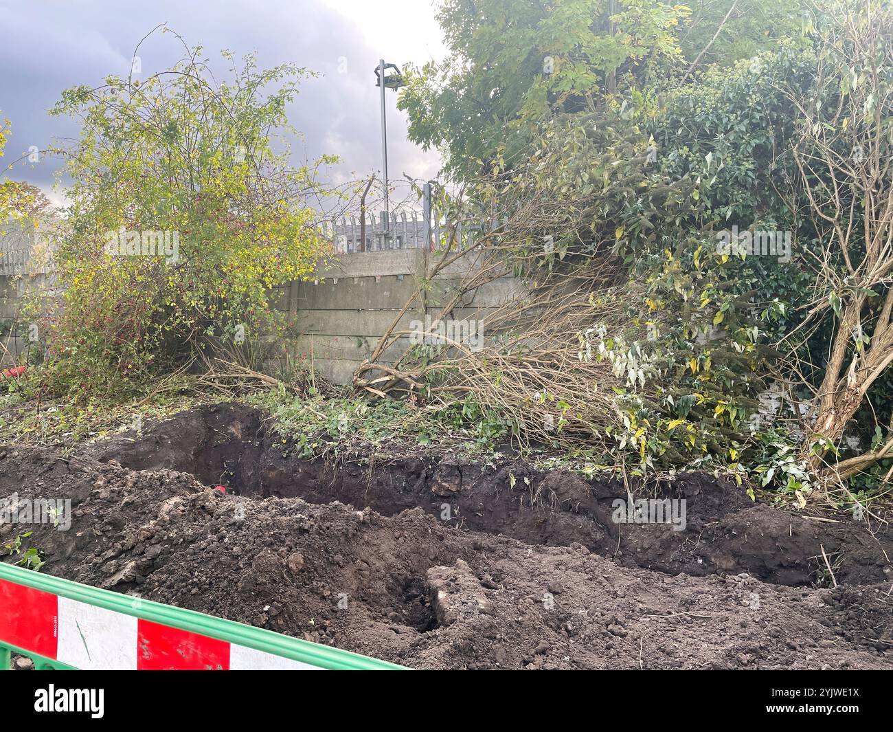 road excavation surrounded by green safety barriers and tools ...
